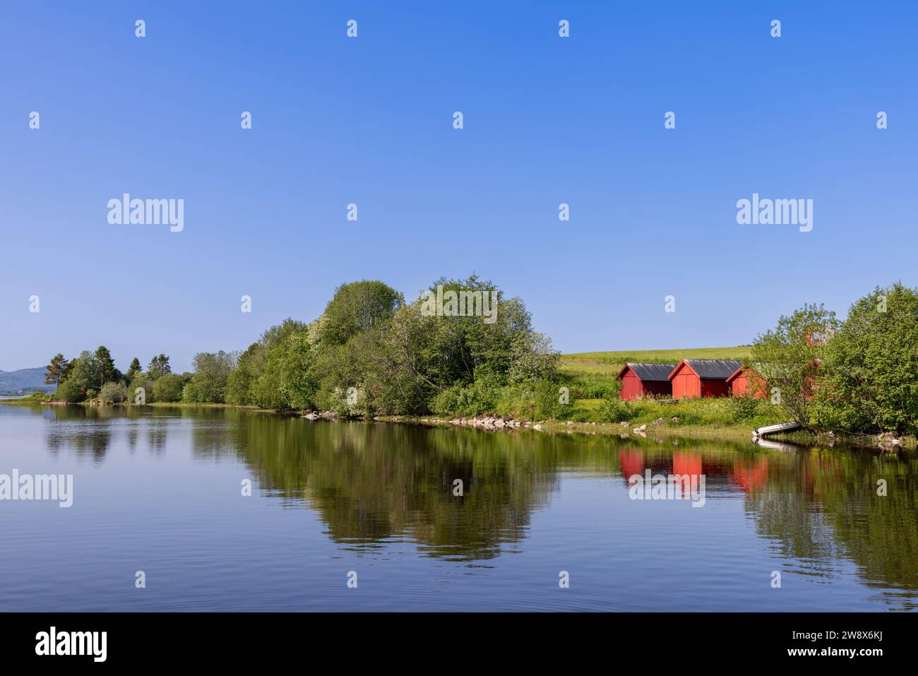 A vibrant summer scene at Snasavatnet, Norway, featuring charming red ...