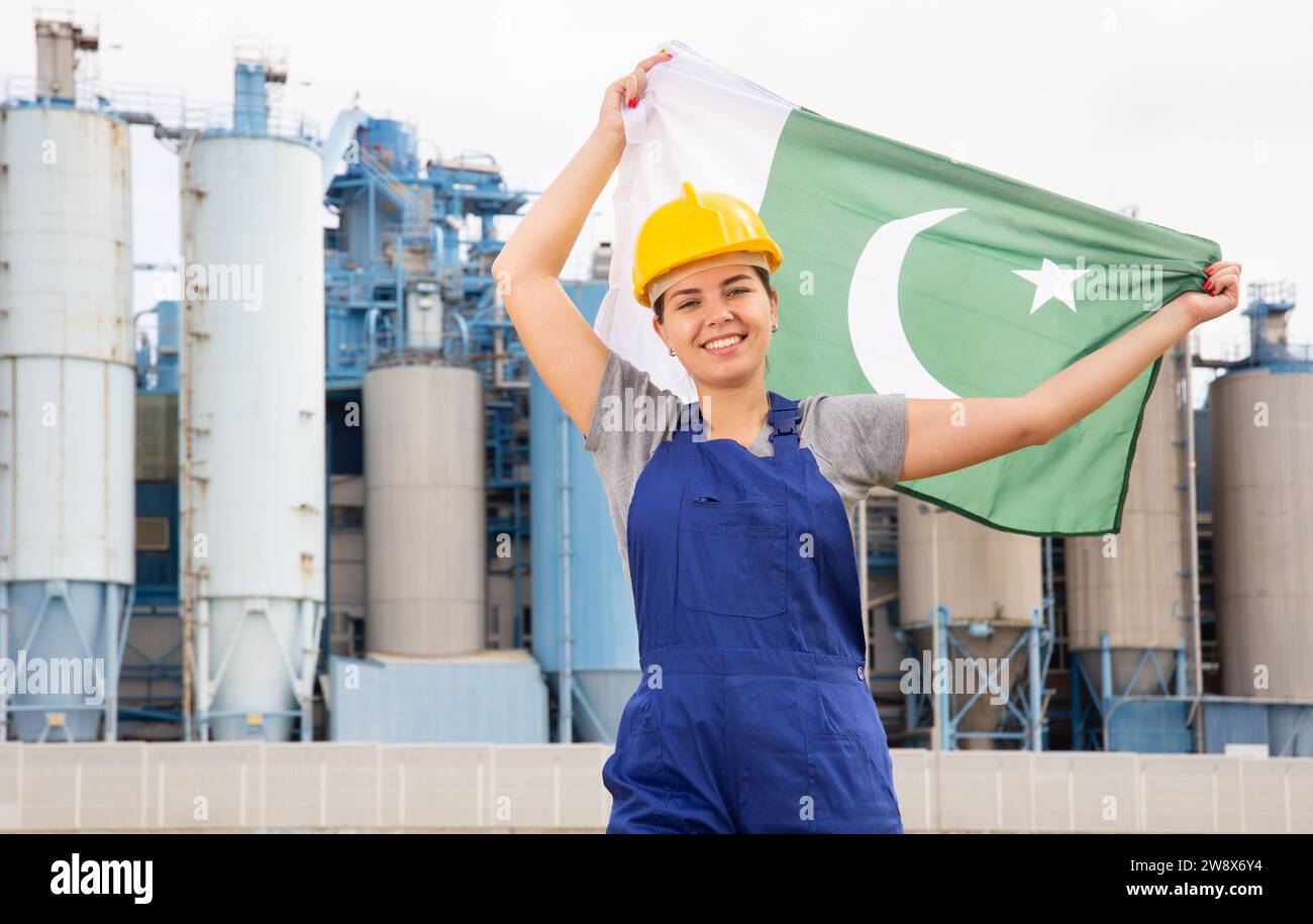 Young female engineer in helmet waving state flag of Pakistan while ...