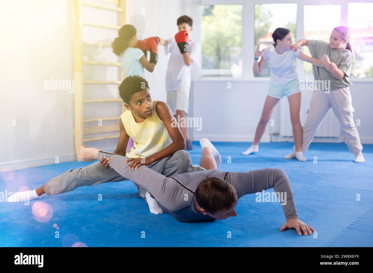 Boy twists the arm of an coach during self-defense training in gym ...