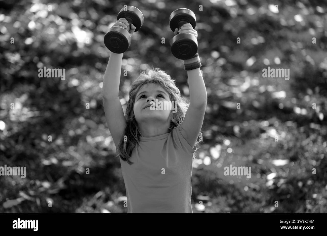 Healthy kid boy with dumbbell exercise outdoor. Little child practice ...
