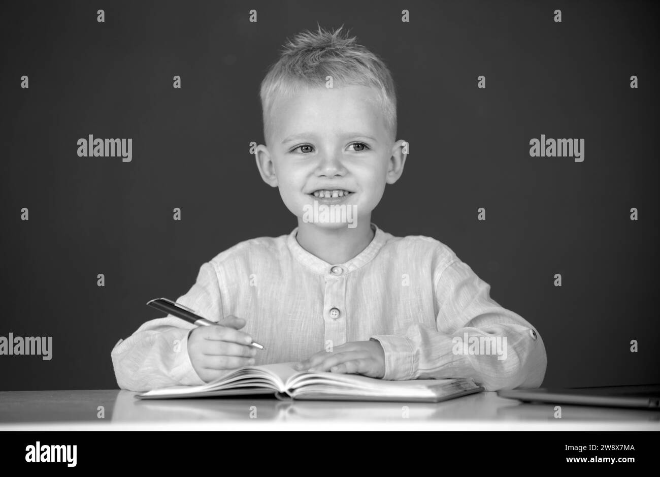 Child at school. Kid is learning in class on background of blackboard ...