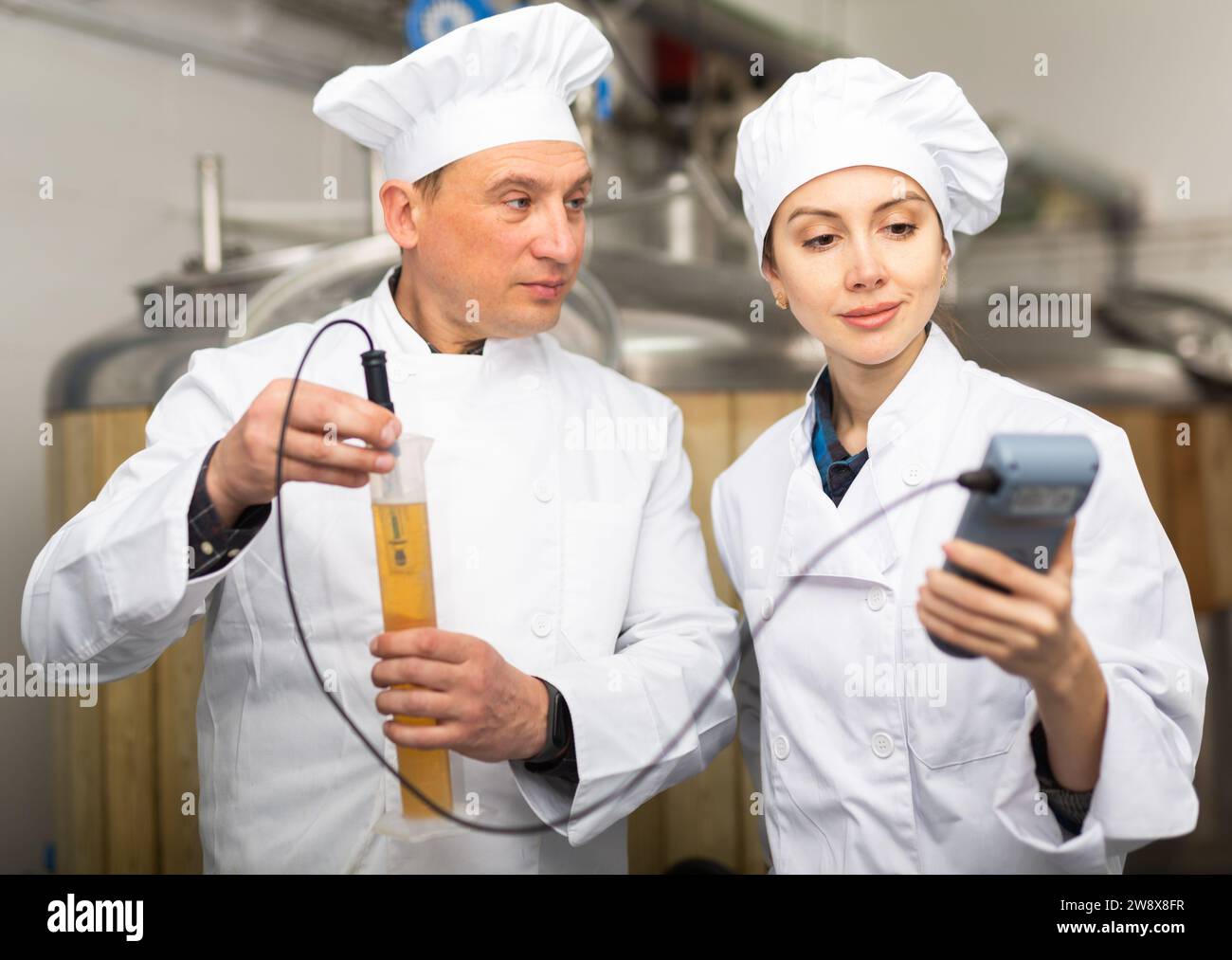 Woman and man check the amount of alcohol in beer with an alcohol meter ...