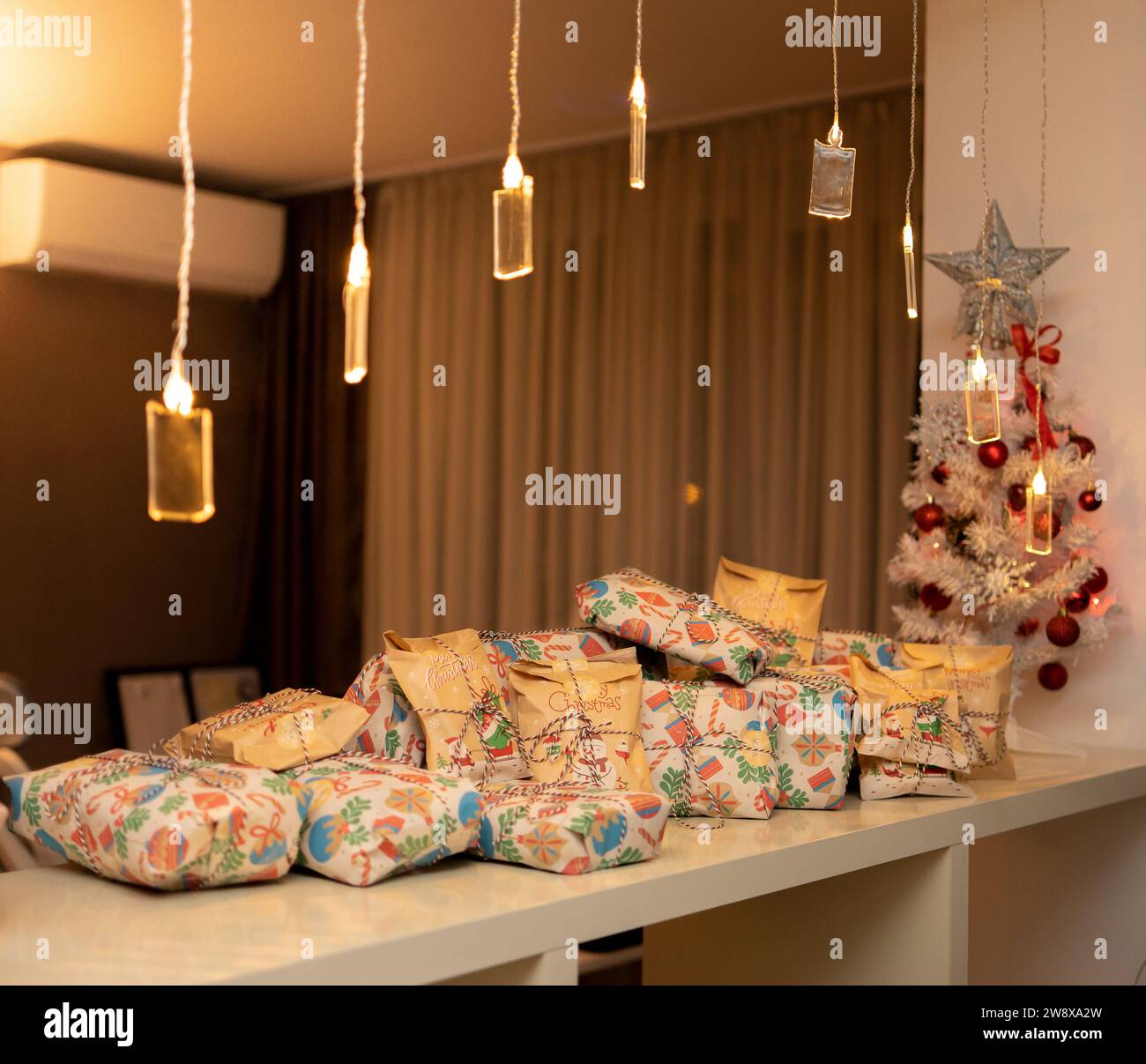 Christmas presents next to tree and lights garland cozy Stock Photo - Alamy