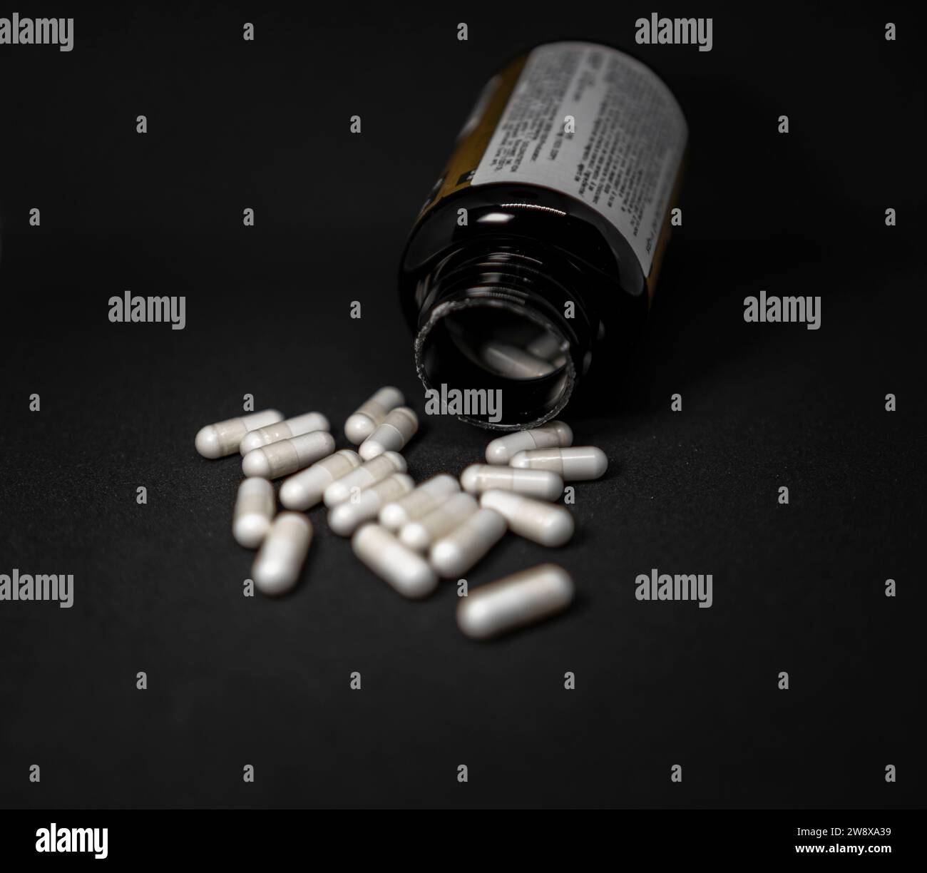 Bottle of pills tipped over black background Stock Photo - Alamy