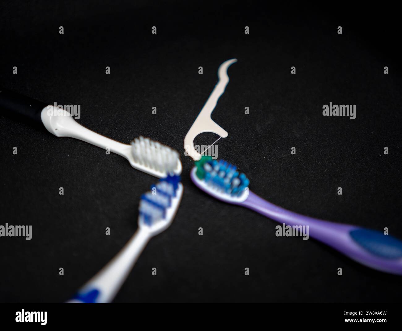 Three toothbrushes and a dental floss instrument Stock Photo - Alamy