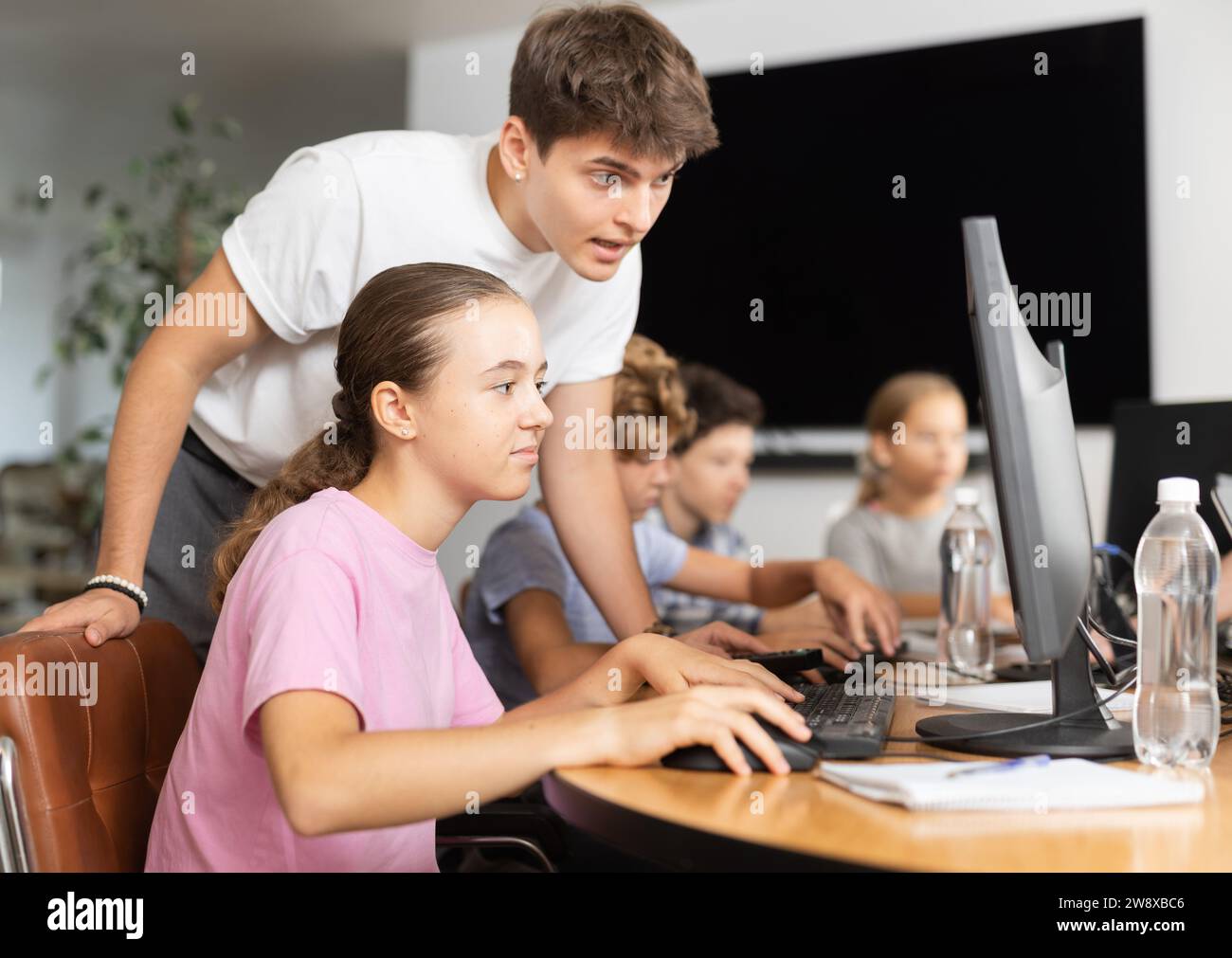 Girl using computer and teacher helping to him in classroom Stock Photo ...