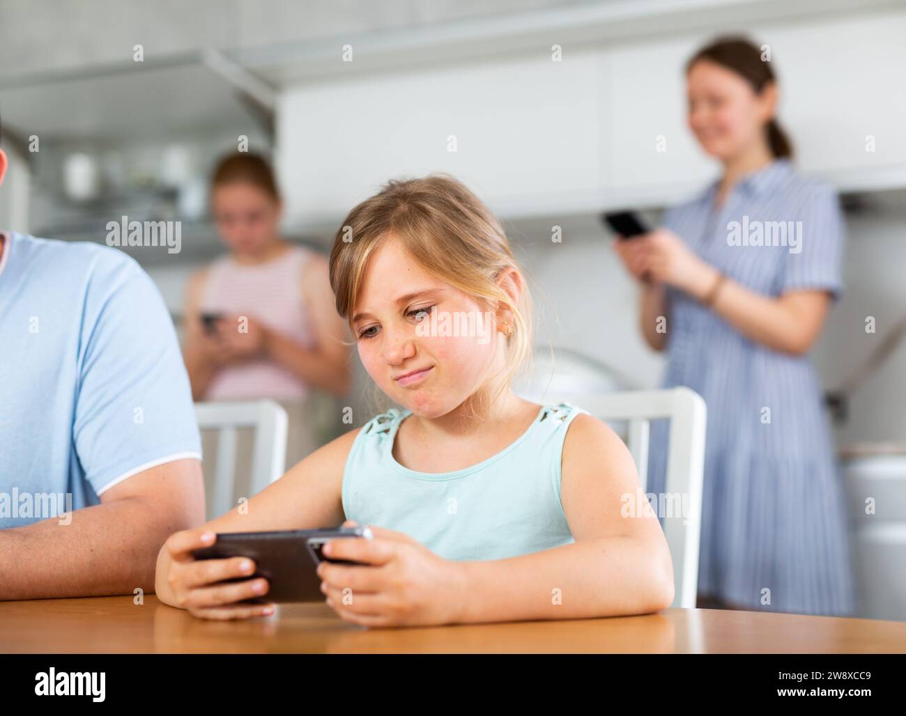 Interested tween girl playing online game on smartphone at table Stock ...
