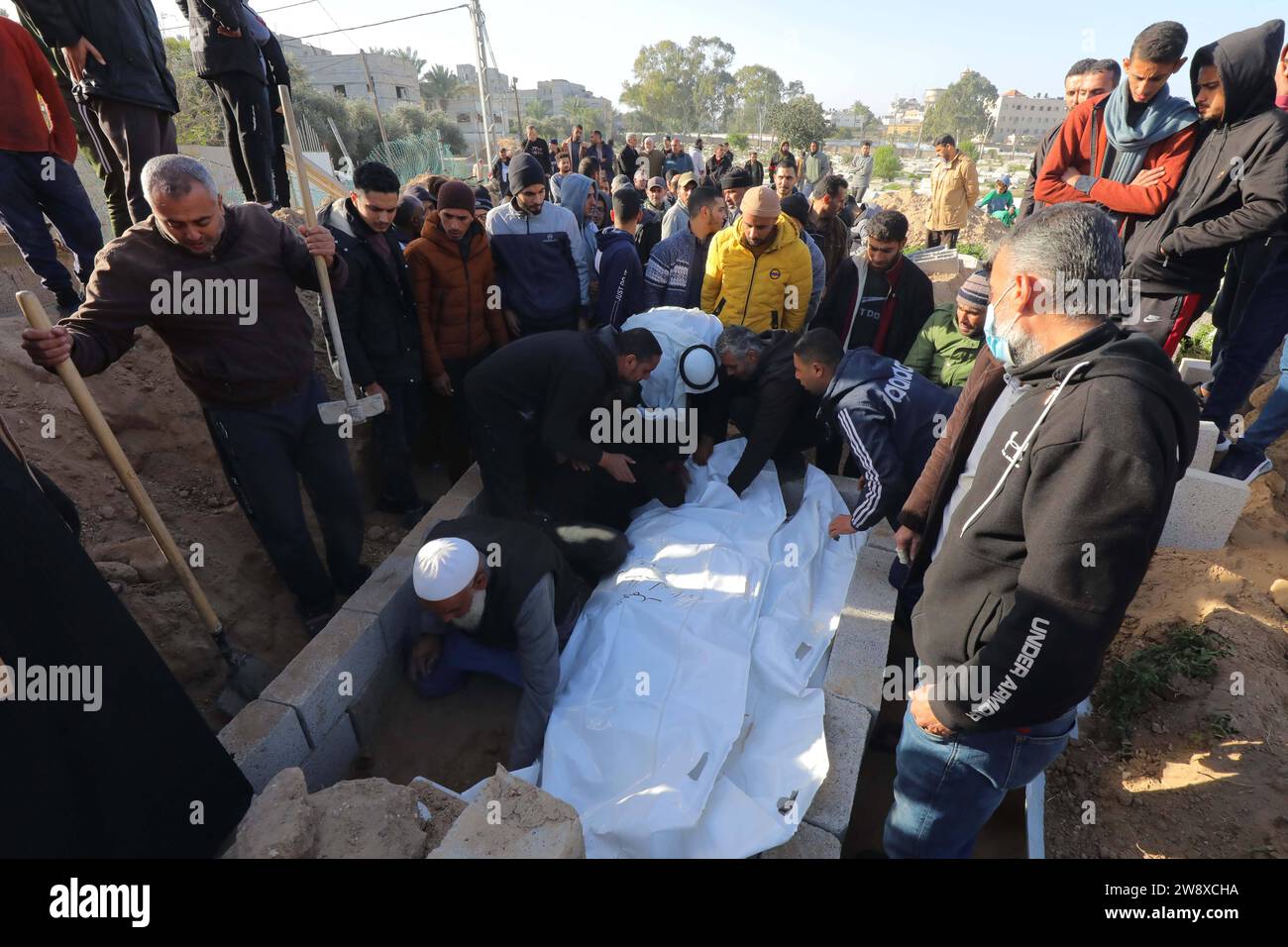 Palestinians bury dead bodies of Palestinian families in a mass grave ...