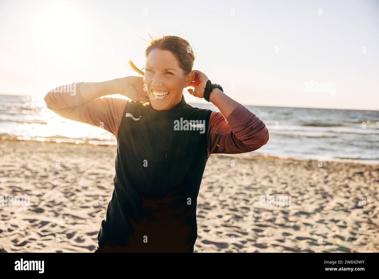 Happy female coach laughing while standing at beach Stock Photo - Alamy