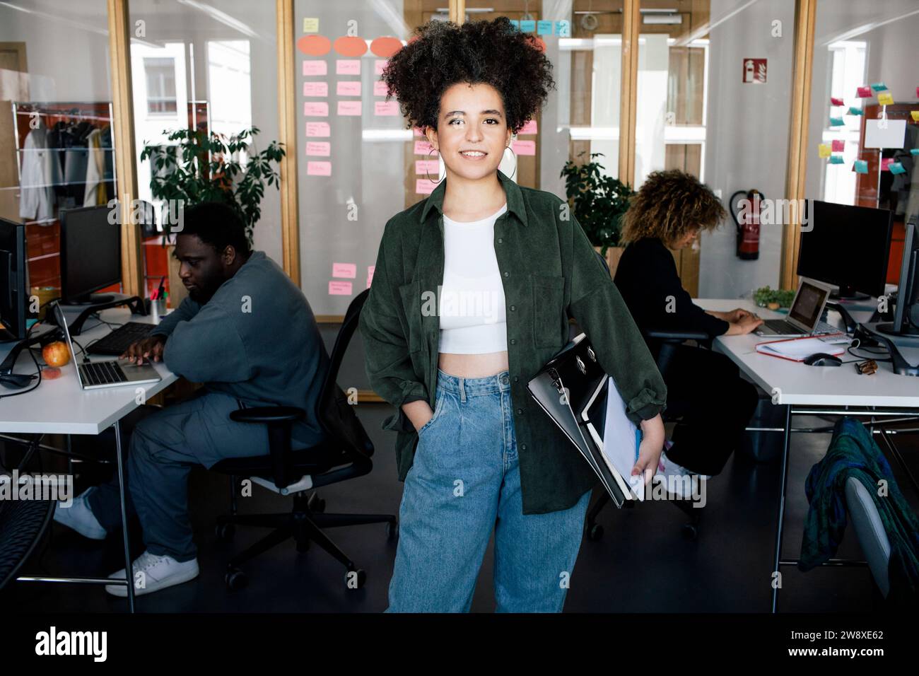 Portrait of confident female computer programmer standing with hand in ...