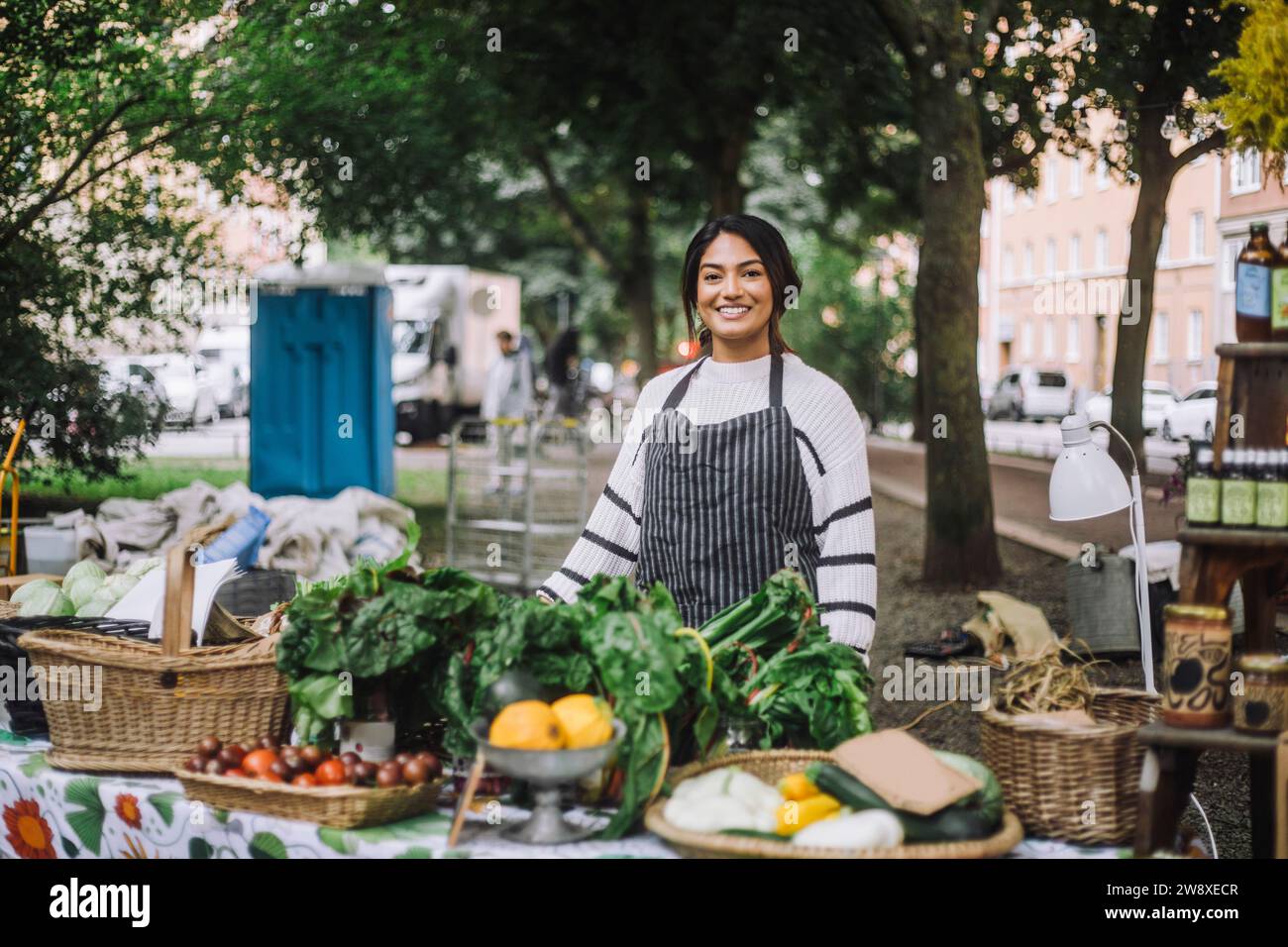 Portrait of smiling female vendor selling vegetables at farmer's market ...