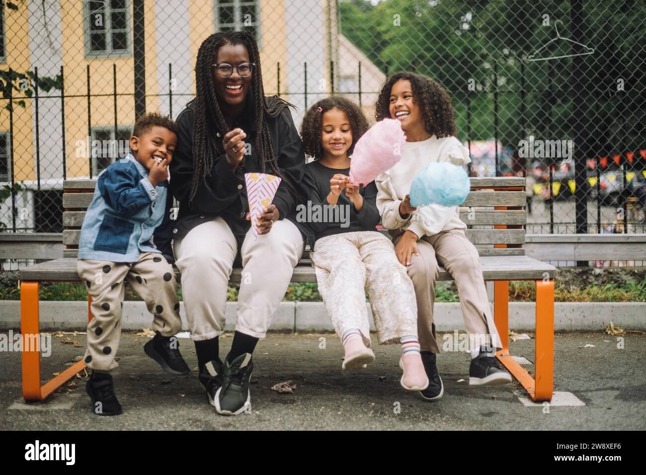 Portrait of happy enjoying with kids eating cotton candies while ...