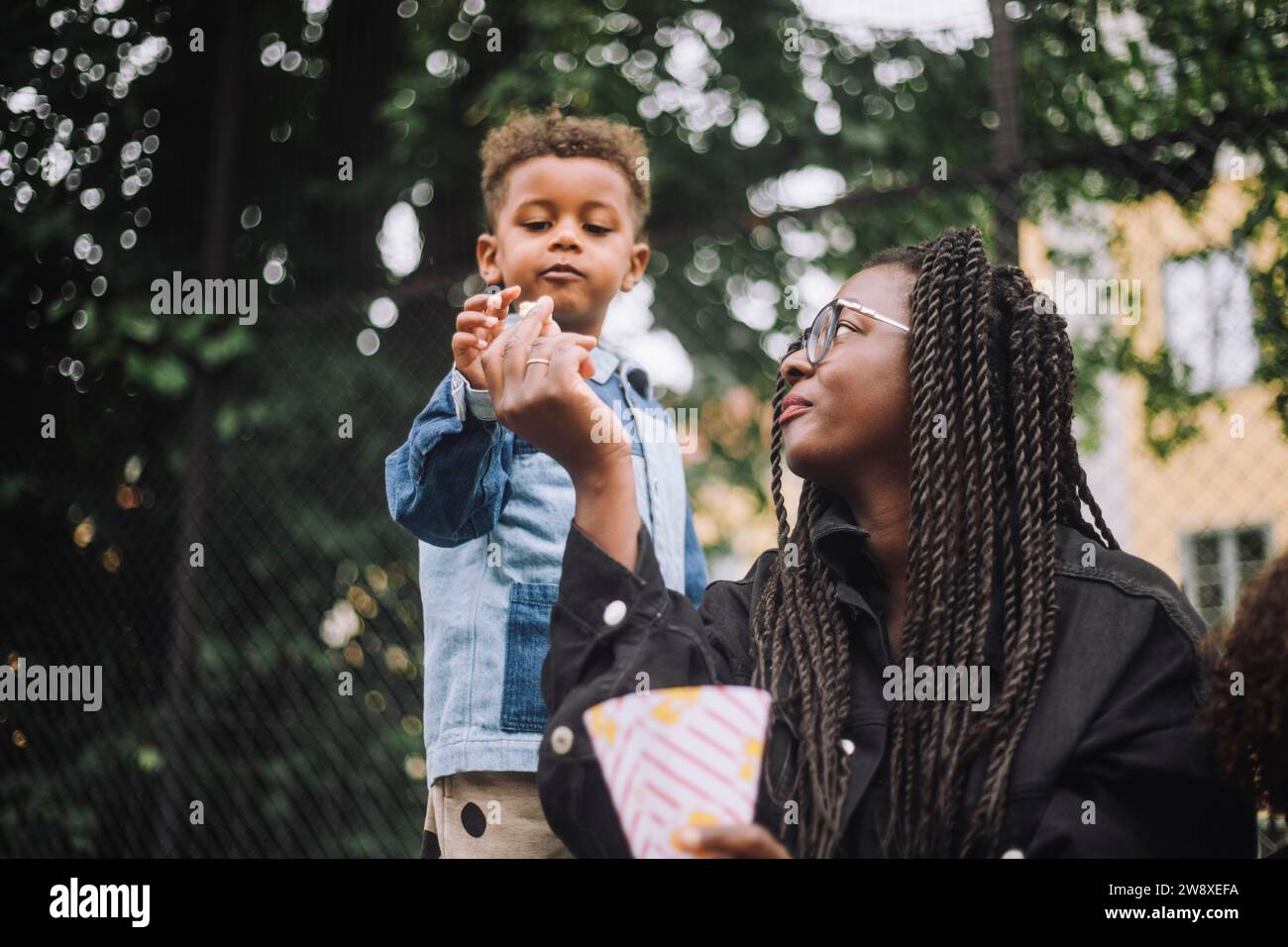 Low angle view of mother giving popcorn to son at amusement park Stock ...