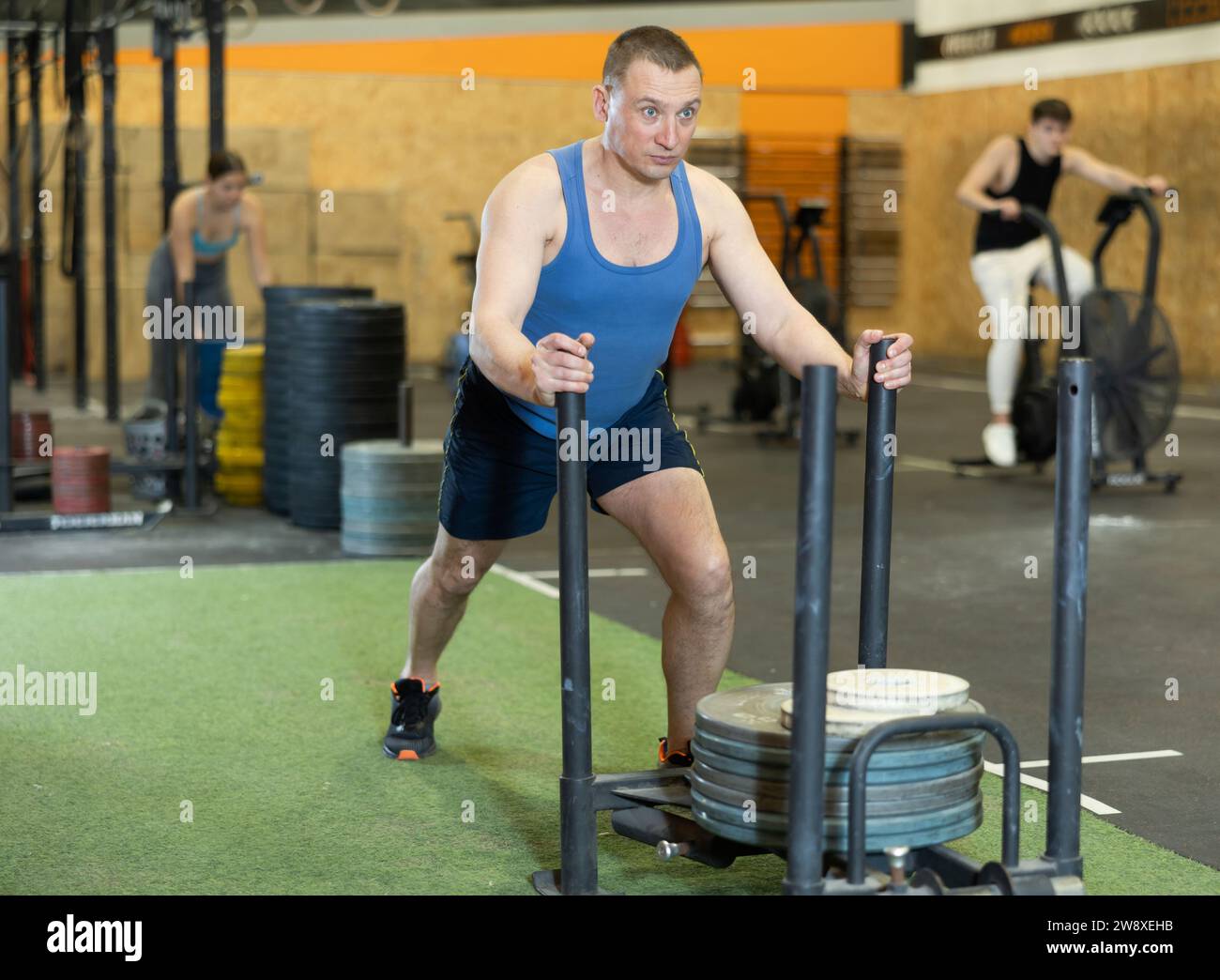 Motivated strong middle-aged man in activewear cross fit equipment on ...