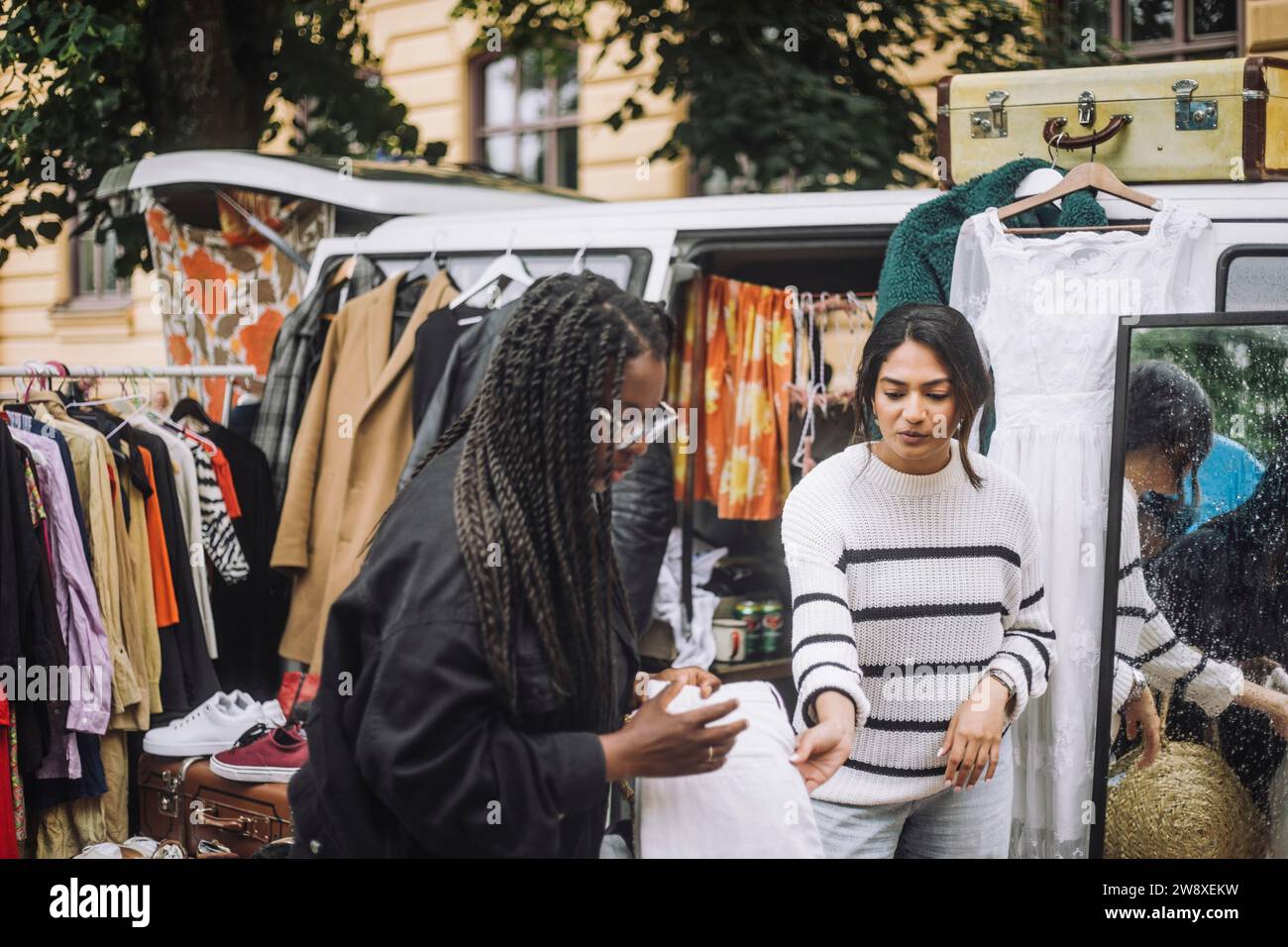 Female owner assisting customer shopping during during second hand sale ...