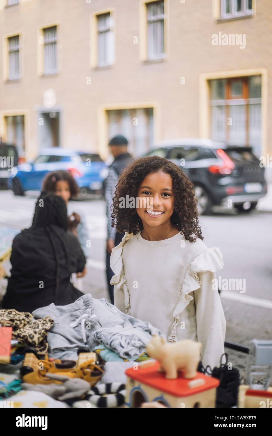 Smiling girl with curly hair neat stall at flea market Stock Photo - Alamy