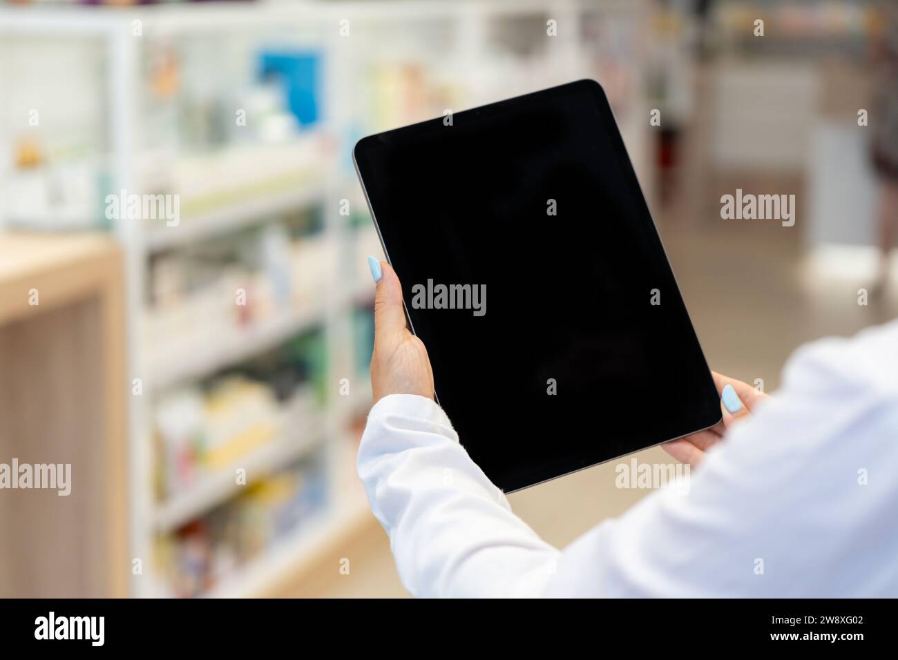 Pharmacist looking at the black screen of a digital tablet in the ...