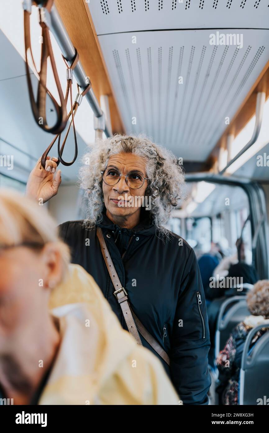 Contemplative female owner looking away while commuting through bus ...