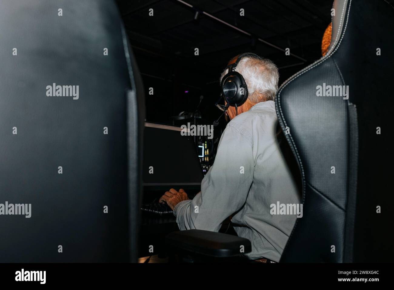 Rear view of elderly man playing game on computer while sitting on ...