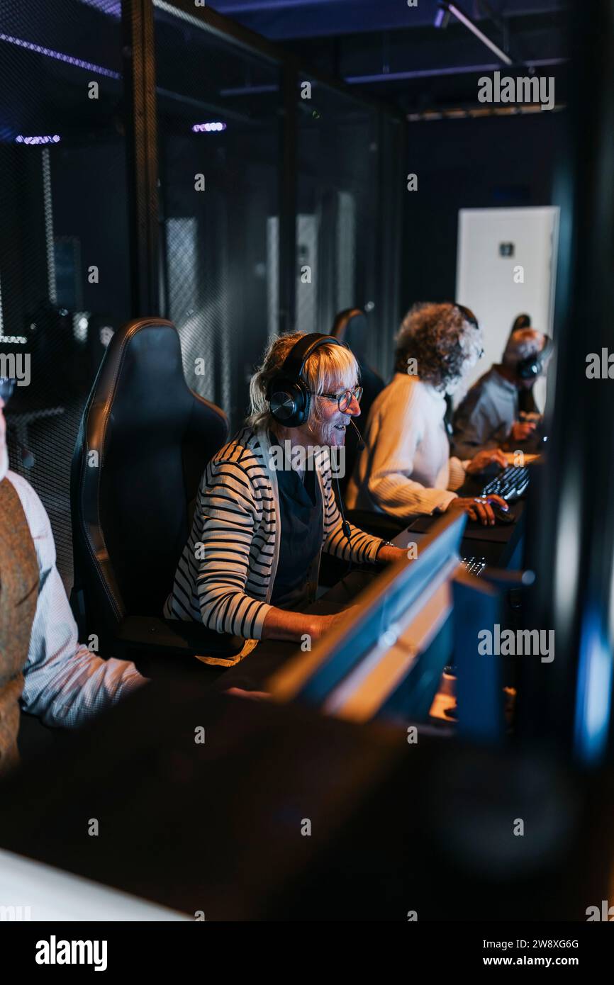 Multiracial elderly male and female friends playing game on computers ...