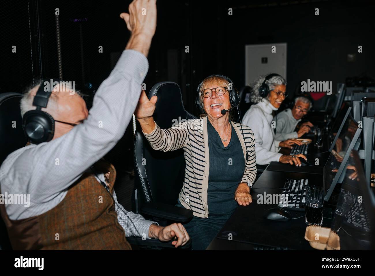 Happy senior couple giving high-five by male and female friends while ...