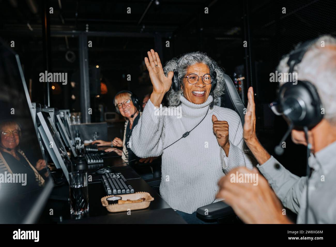 Happy senior couple giving high-five while winning video game at gaming ...