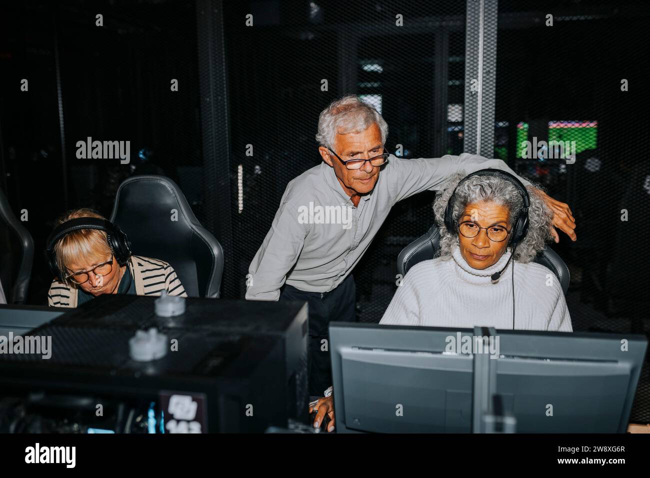 Elderly woman playing video game on computer by male and female friends ...