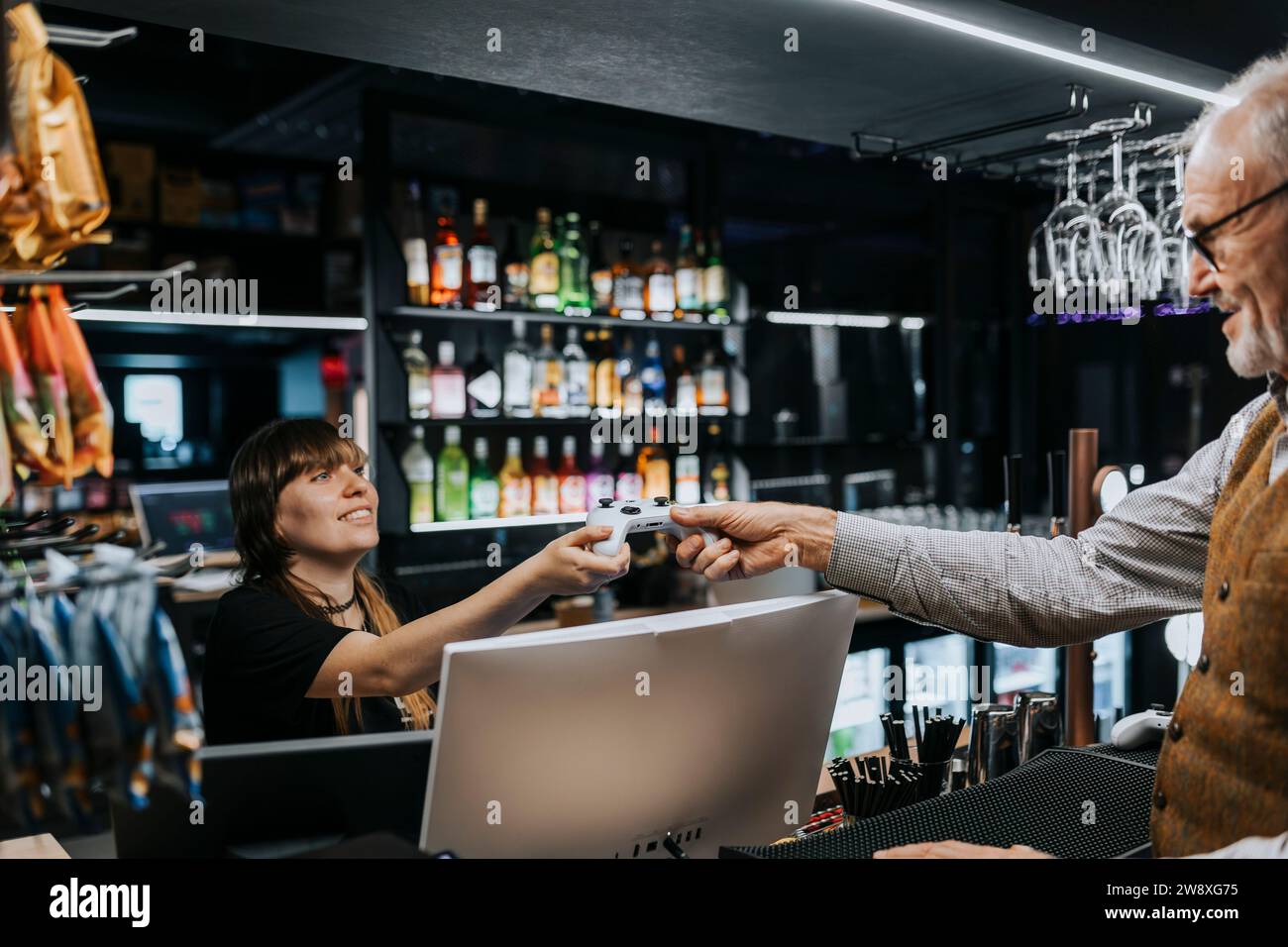 Young saleswoman giving game controller to male customer at gaming ...