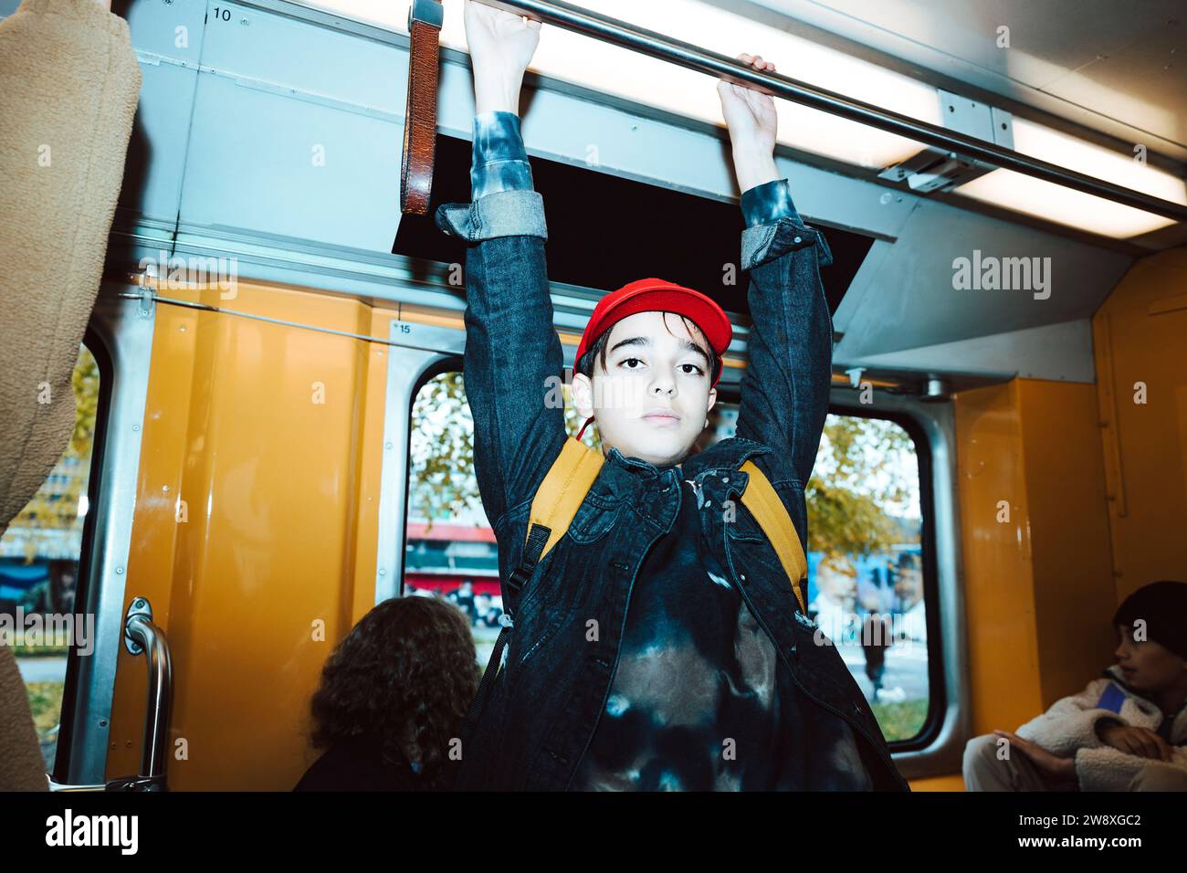 Portrait of boy holding handle while traveling in tram on weekend Stock ...