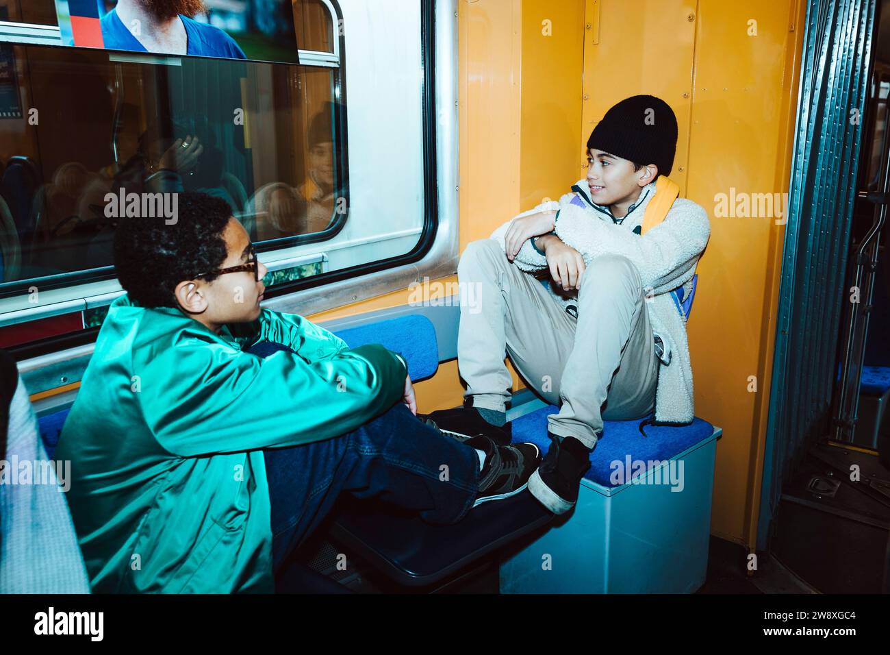 Male friends talking with each other while sitting in tram Stock Photo ...