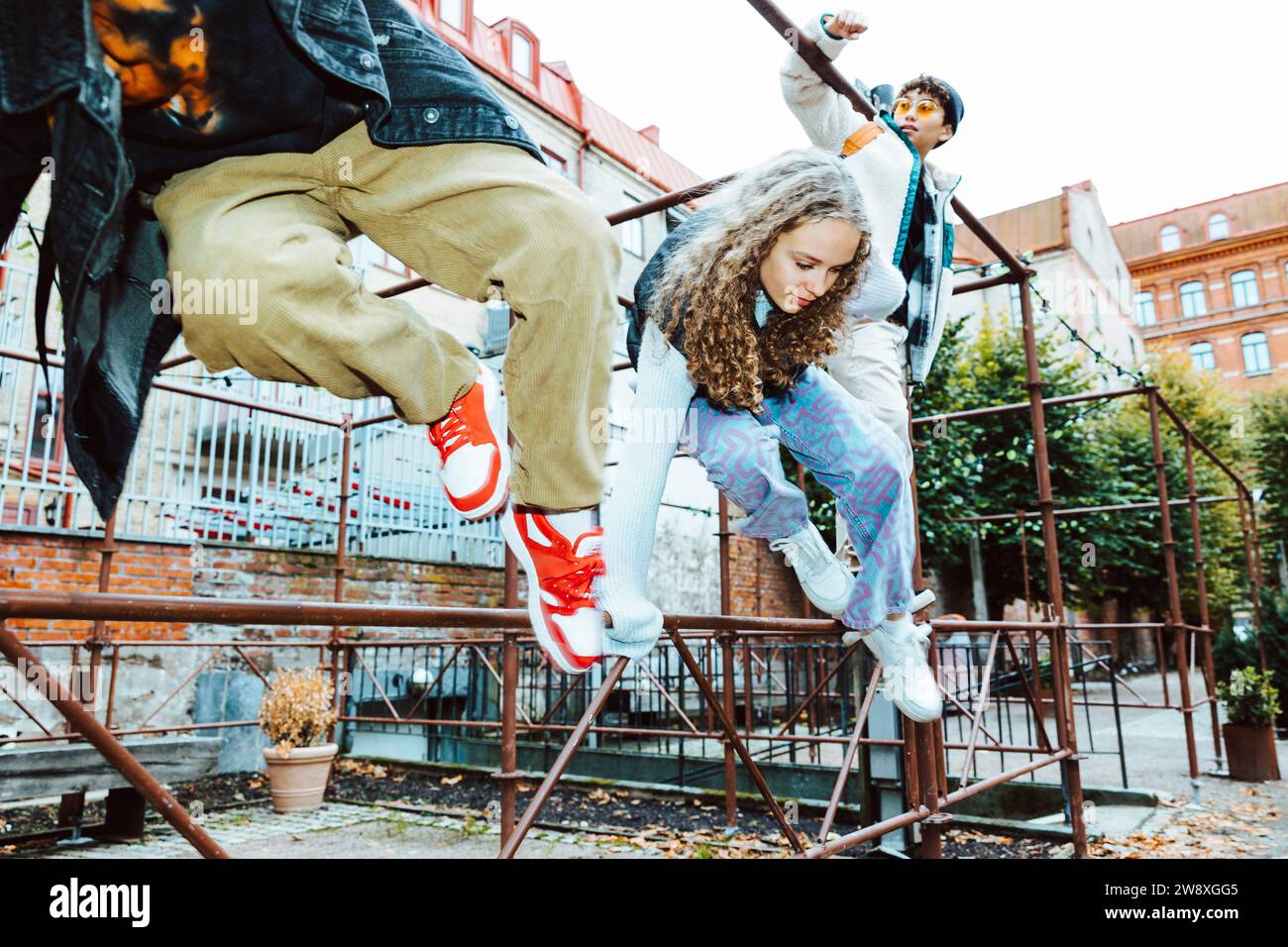 Male and female friends jumping over railing against building Stock ...