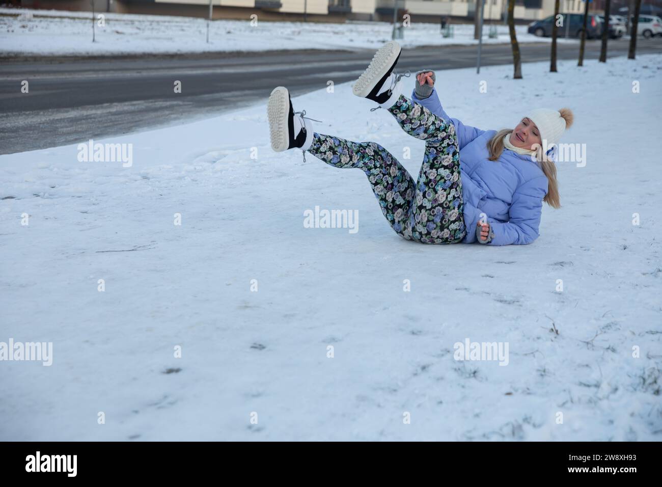 The young person lost her balance on the slippery sidewalk and fell on ...