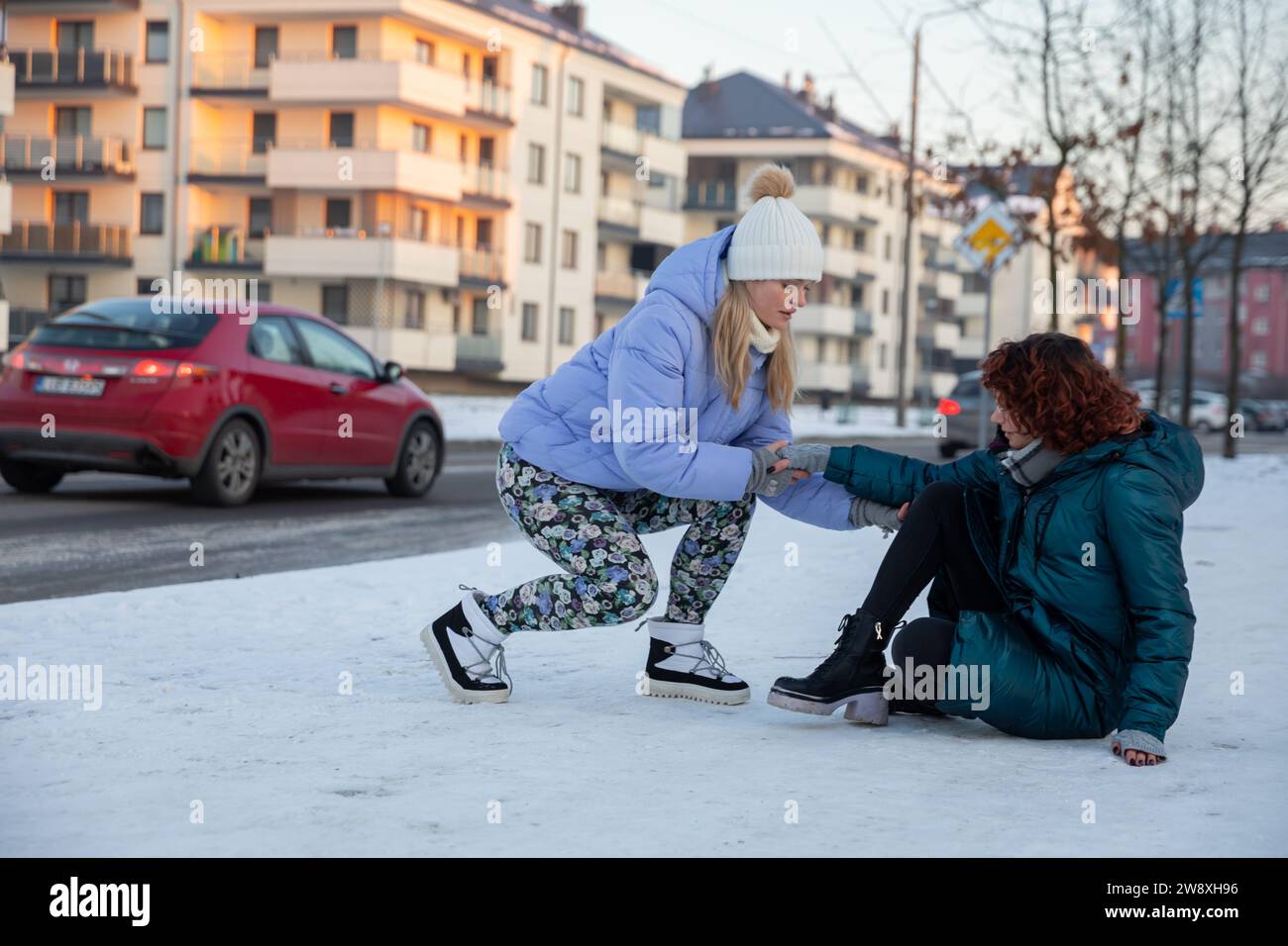 A kind neighbor helps a woman who has fallen in the snow get up Stock ...