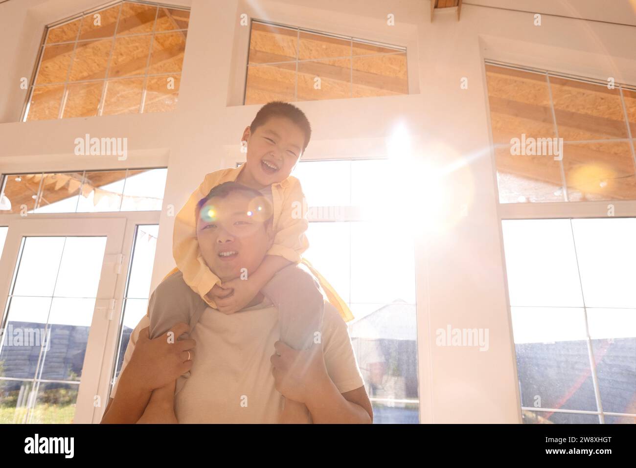 Laughing Asian dad and son have fun together at home. A cute little boy ...