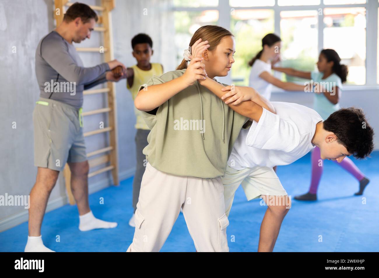 Tween girl practicing armlock in sparring with boy during self-defense ...