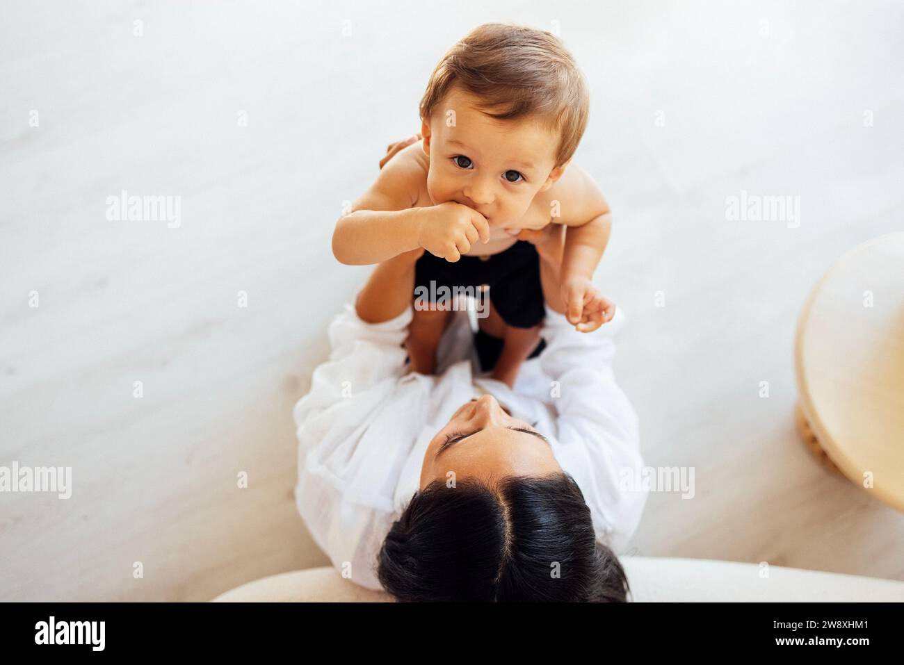 A young mother holds her cute little boy in her arms. A charming woman ...