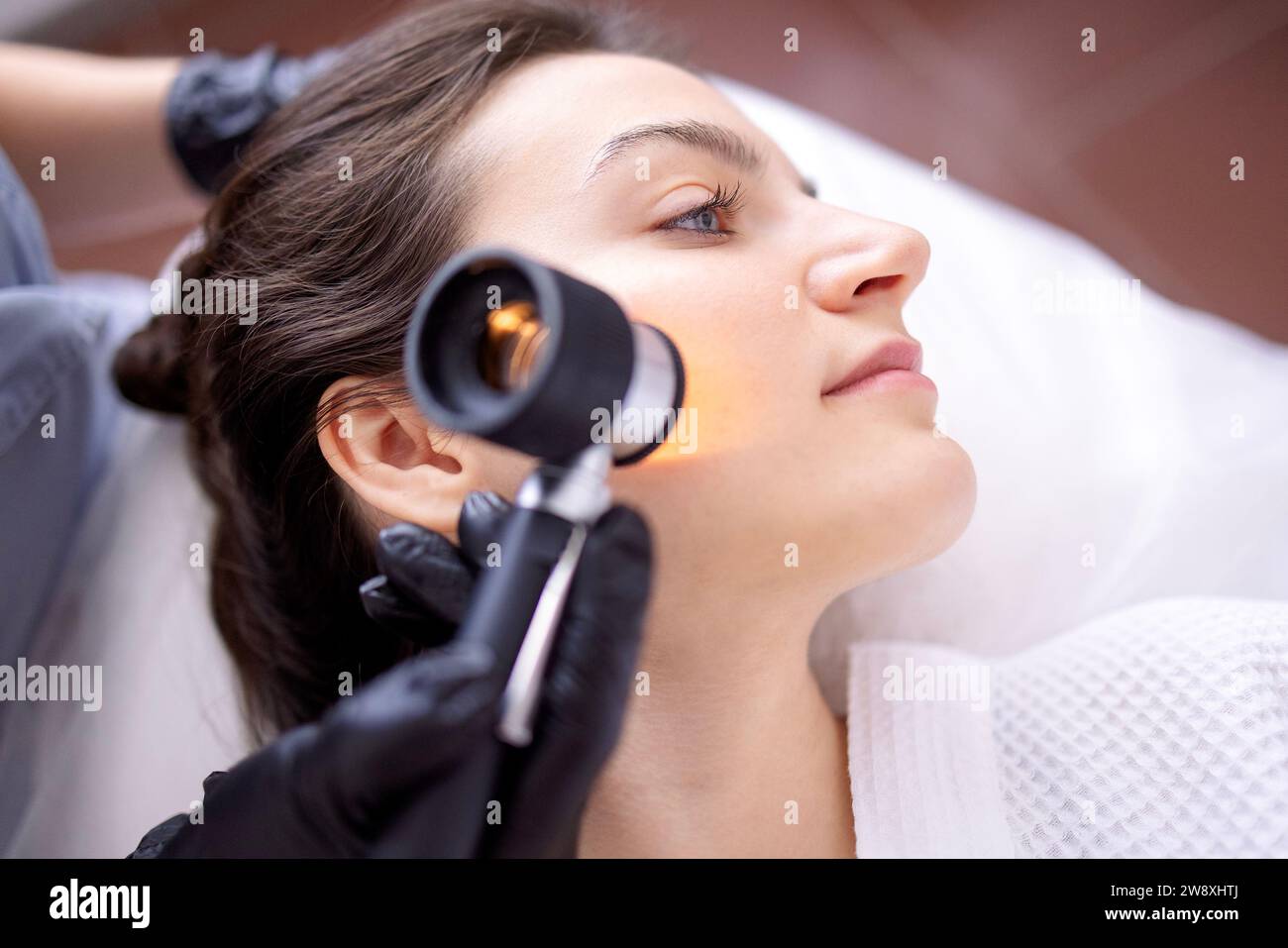 Doctor dermatologist examines skin of client face of beauty salon with ...