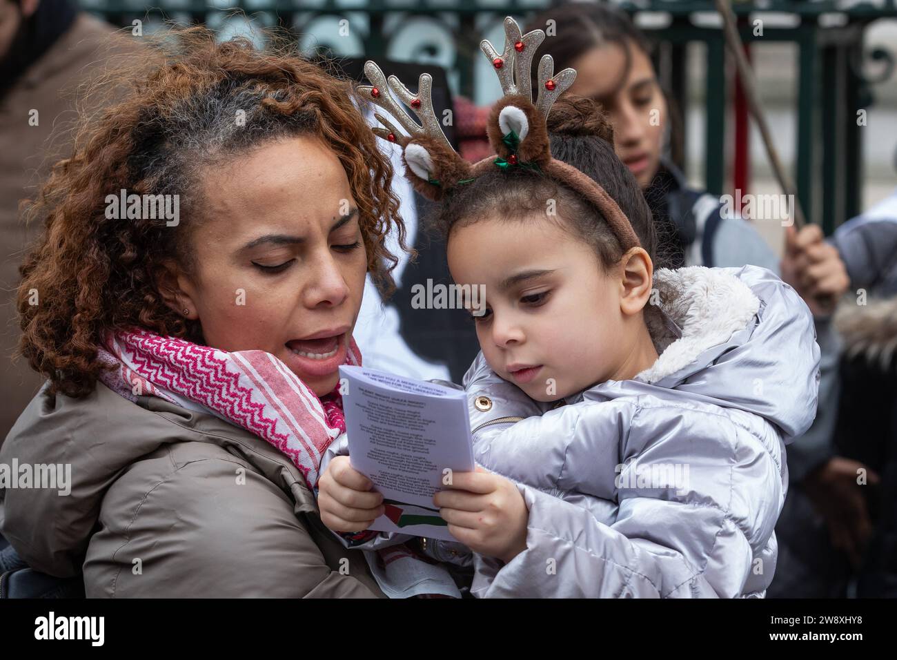 London, UK. 22nd December, 2023. A parent and child sing an adapted ...