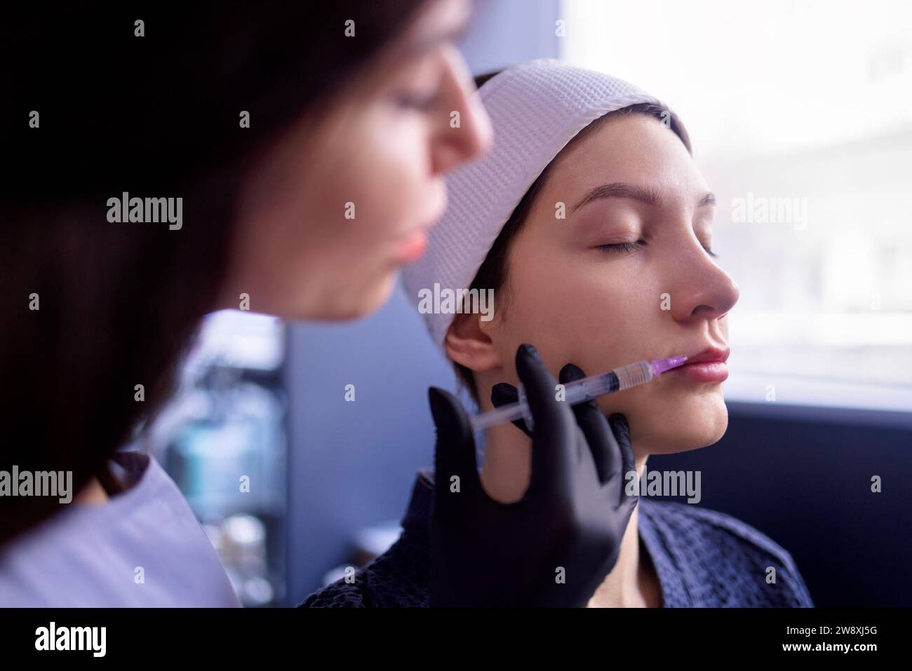 Beauty injections. Female cosmetologist in black gloves makes an ...