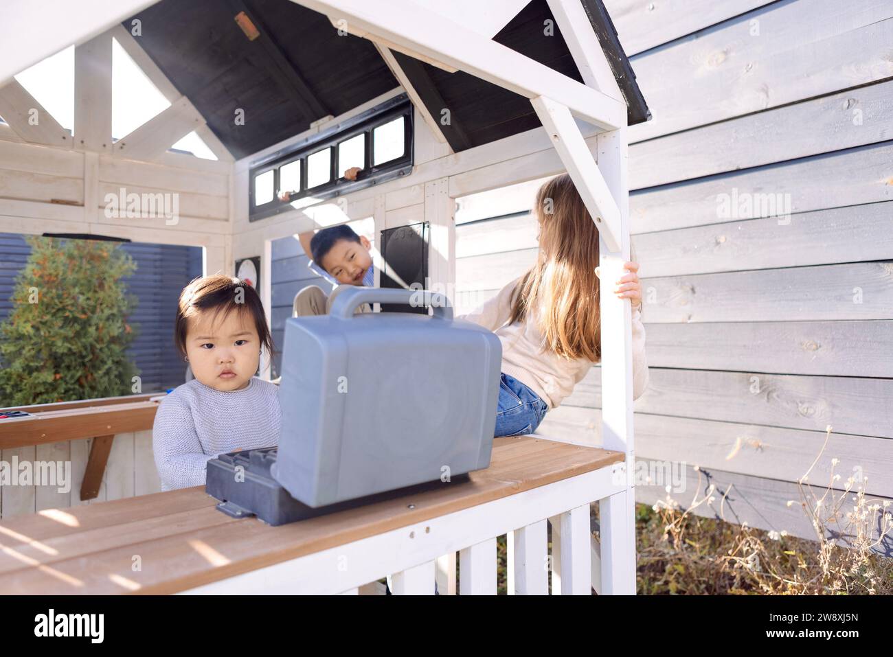 Three small children are playing in a wooden children house. Asian and ...