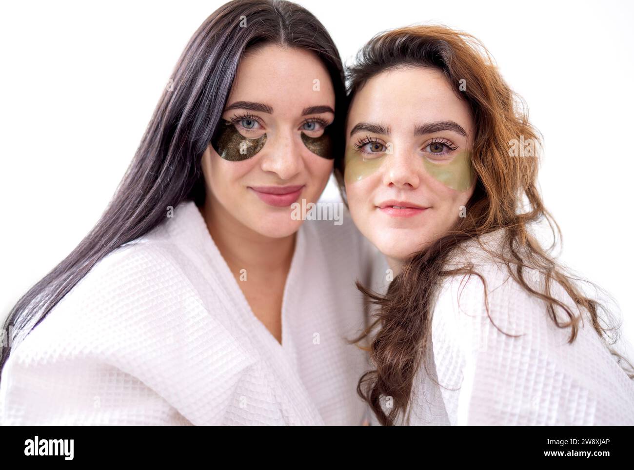 Two young female friends clients of beauty salon in white coats ...