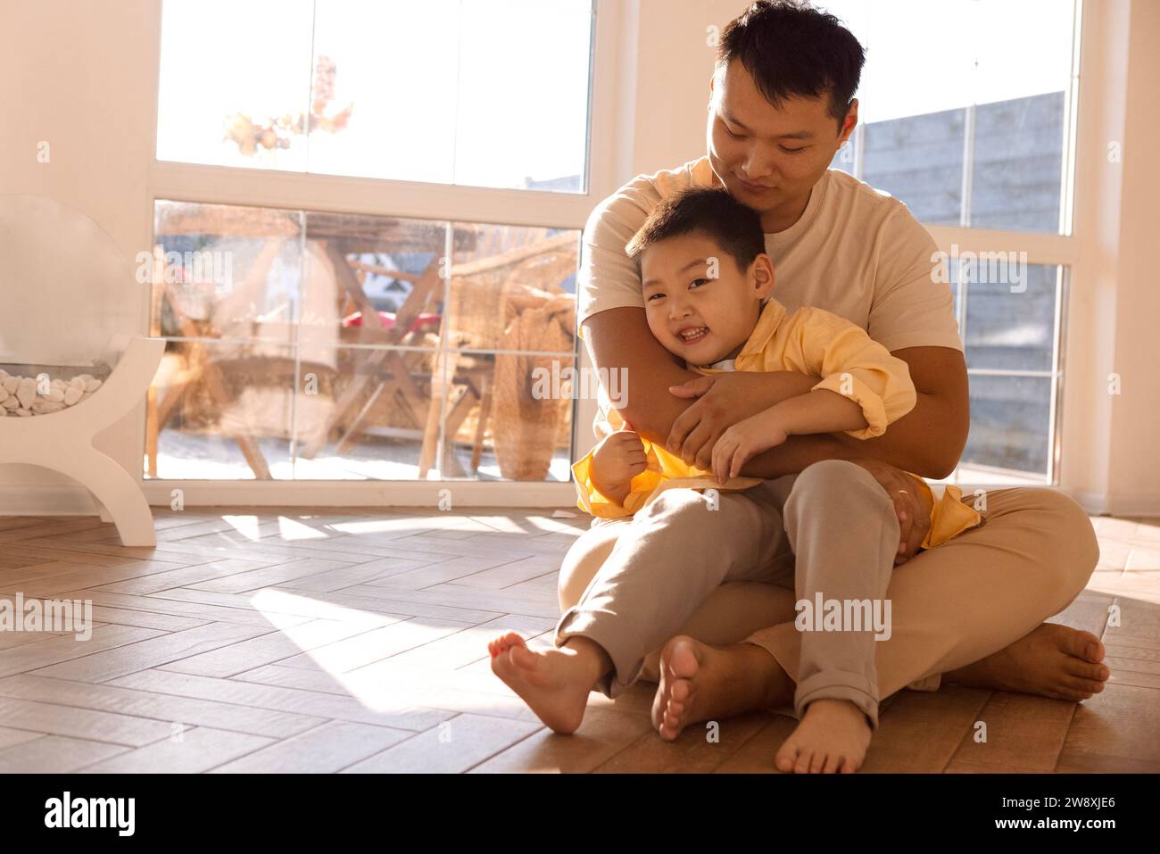 A young happy Asian man hugs his little son. A Korean dad is playing ...