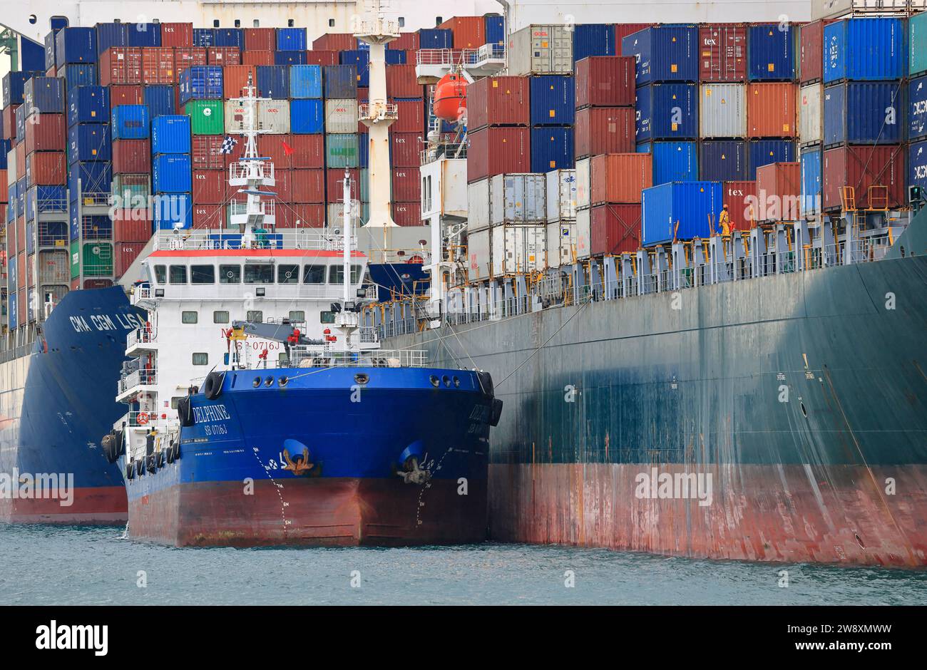 A small transport ship docks next to a Large container ship Stock Photo ...