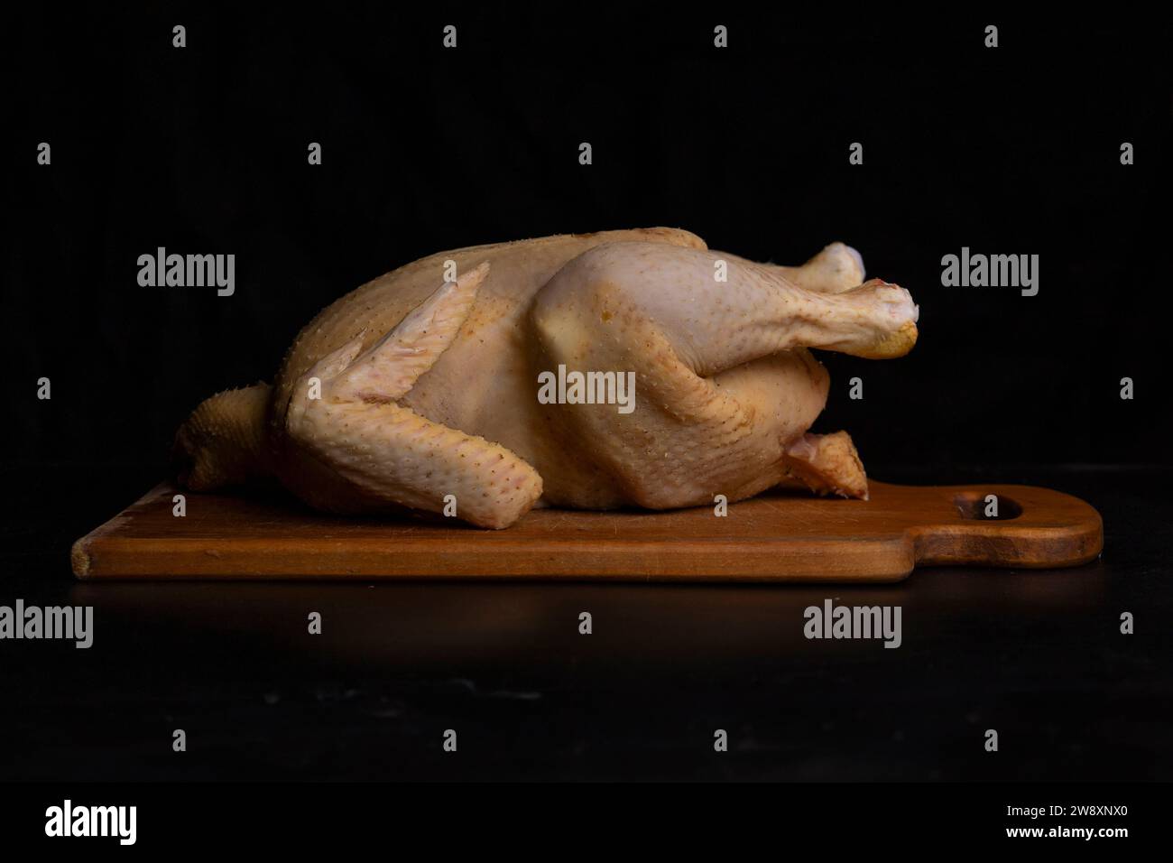 Chicken carcass on a board on a black background Stock Photo - Alamy