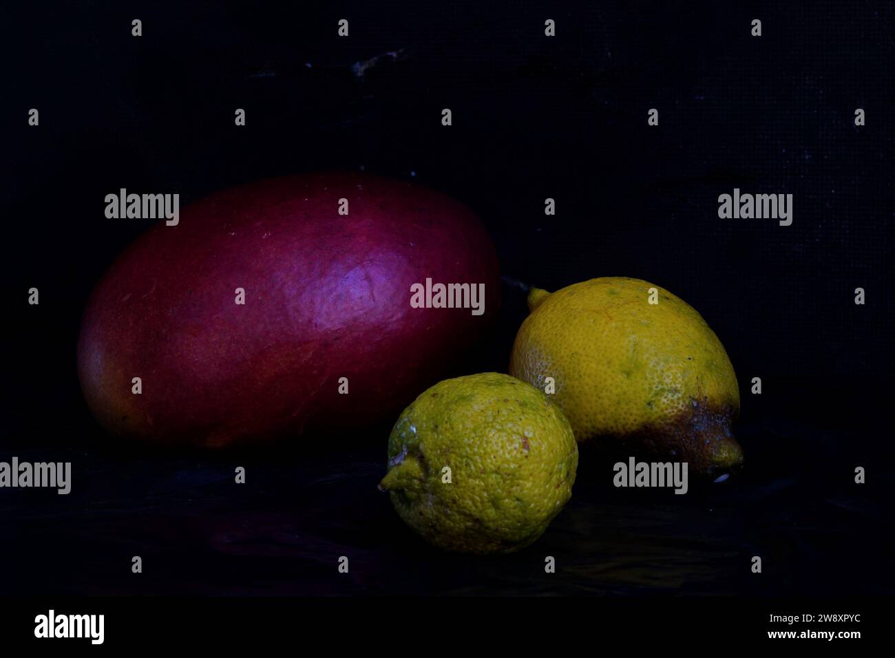 Still life with red mango, yellow lemons and dark background Stock ...