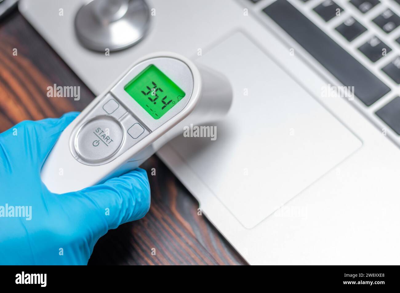 The technician applies an infrared thermometer to the laptop panel ...