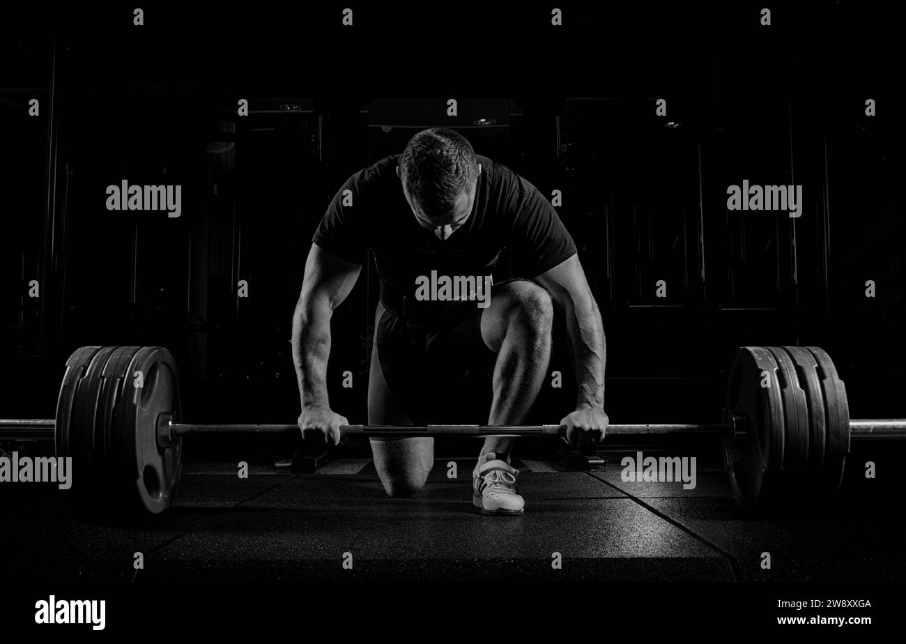 Professional athlete bent over the barbell and is preparing to lift a ...