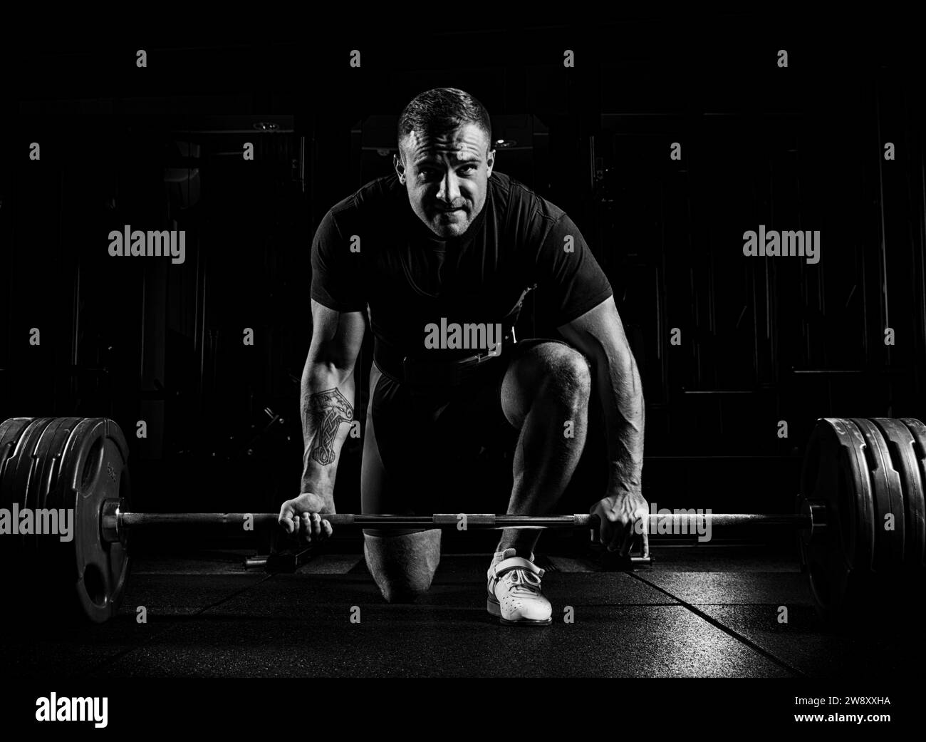 Professional athlete bent over the barbell and is preparing to lift a ...