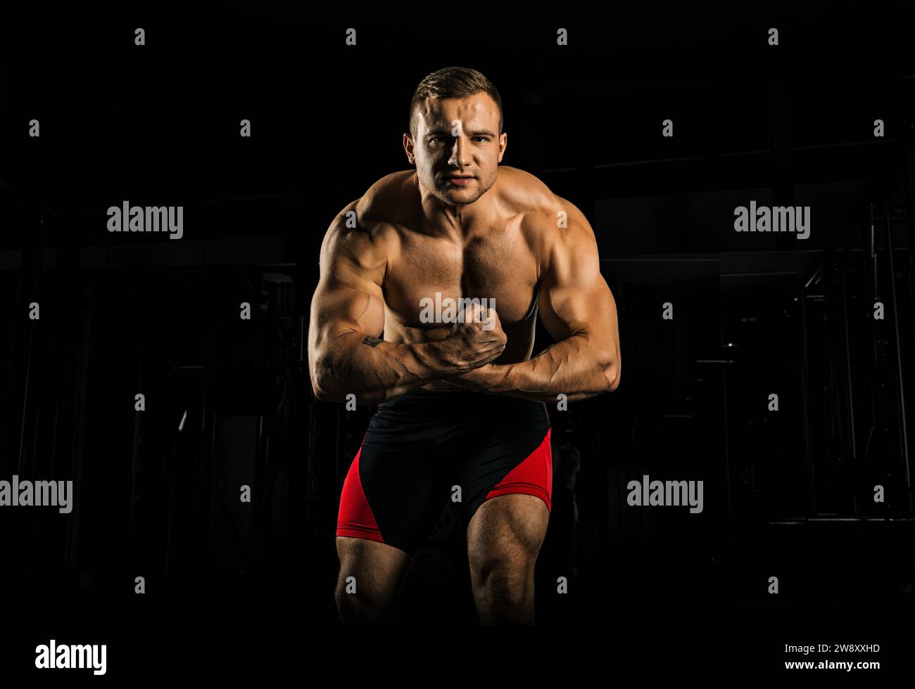 The weightlifter is posing in front of the camera, monstrously ...