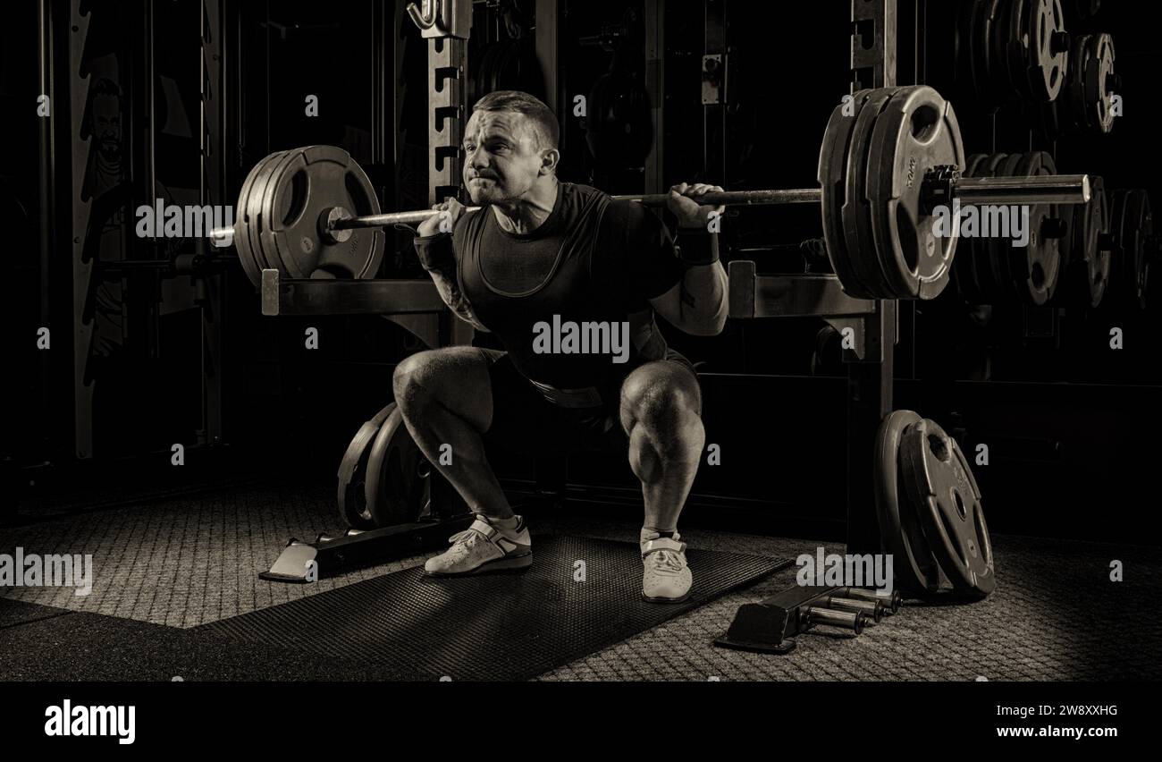 The weightlifter is getting ready to stand with a heavy barbell. Is at ...